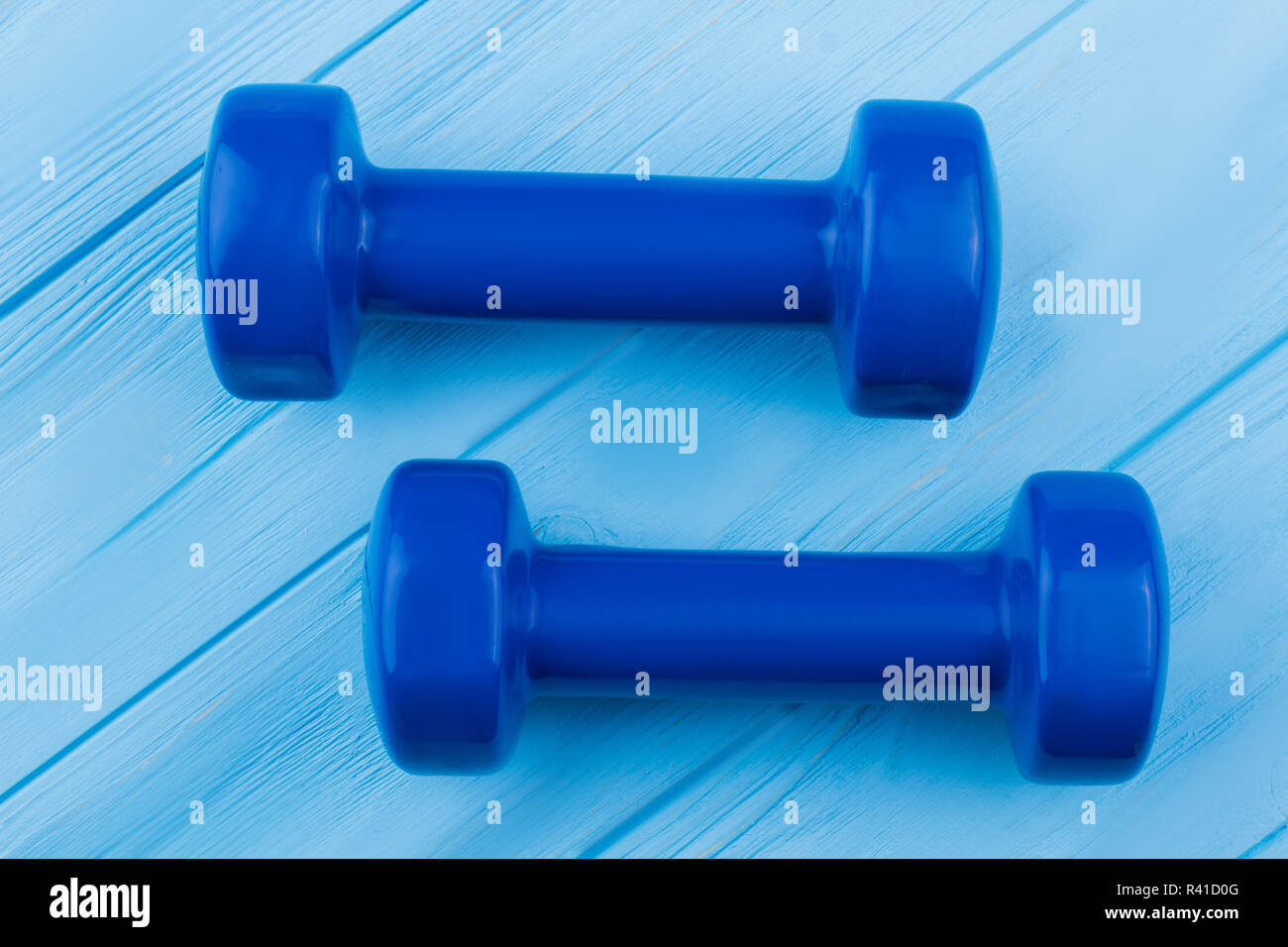 Pair of small dumbbells on wooden background. Two blue dumbbells on ...