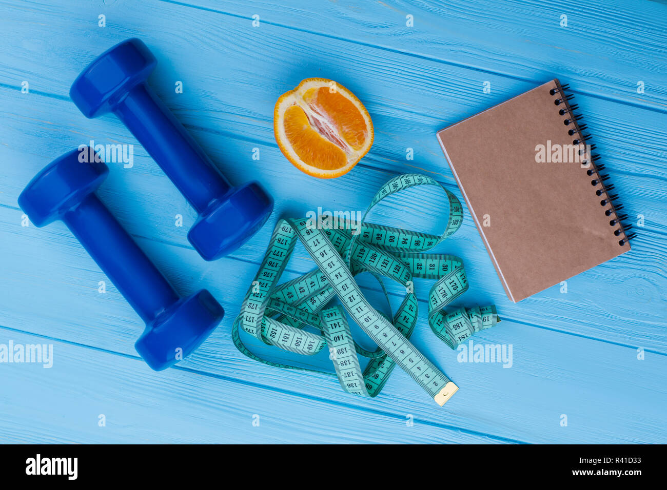 Diet and weight loss concept. Dumbbells, measuring tape, orange fruit ...
