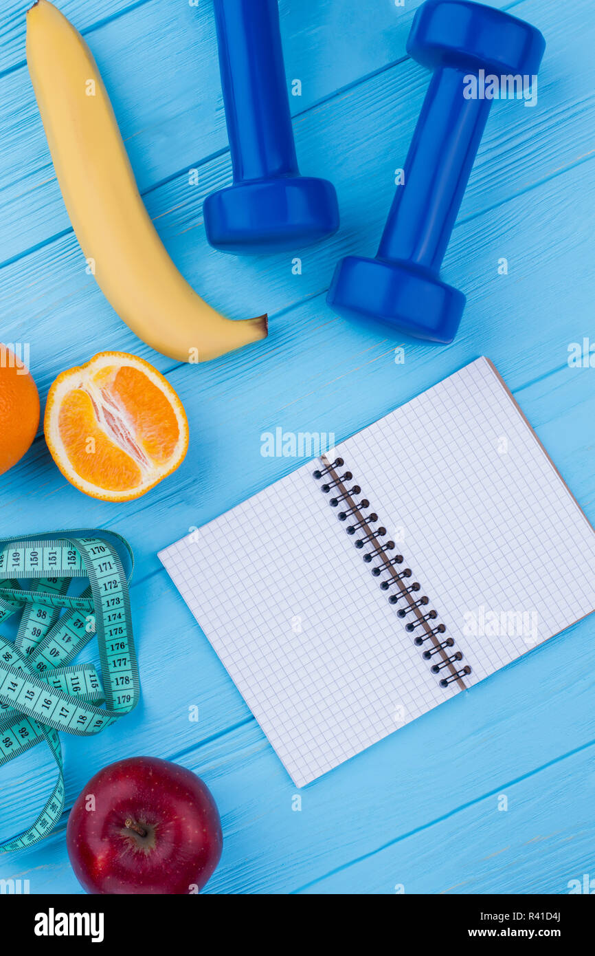 Fitness equipment and fruits on blue wooden background. Dumbbells ...