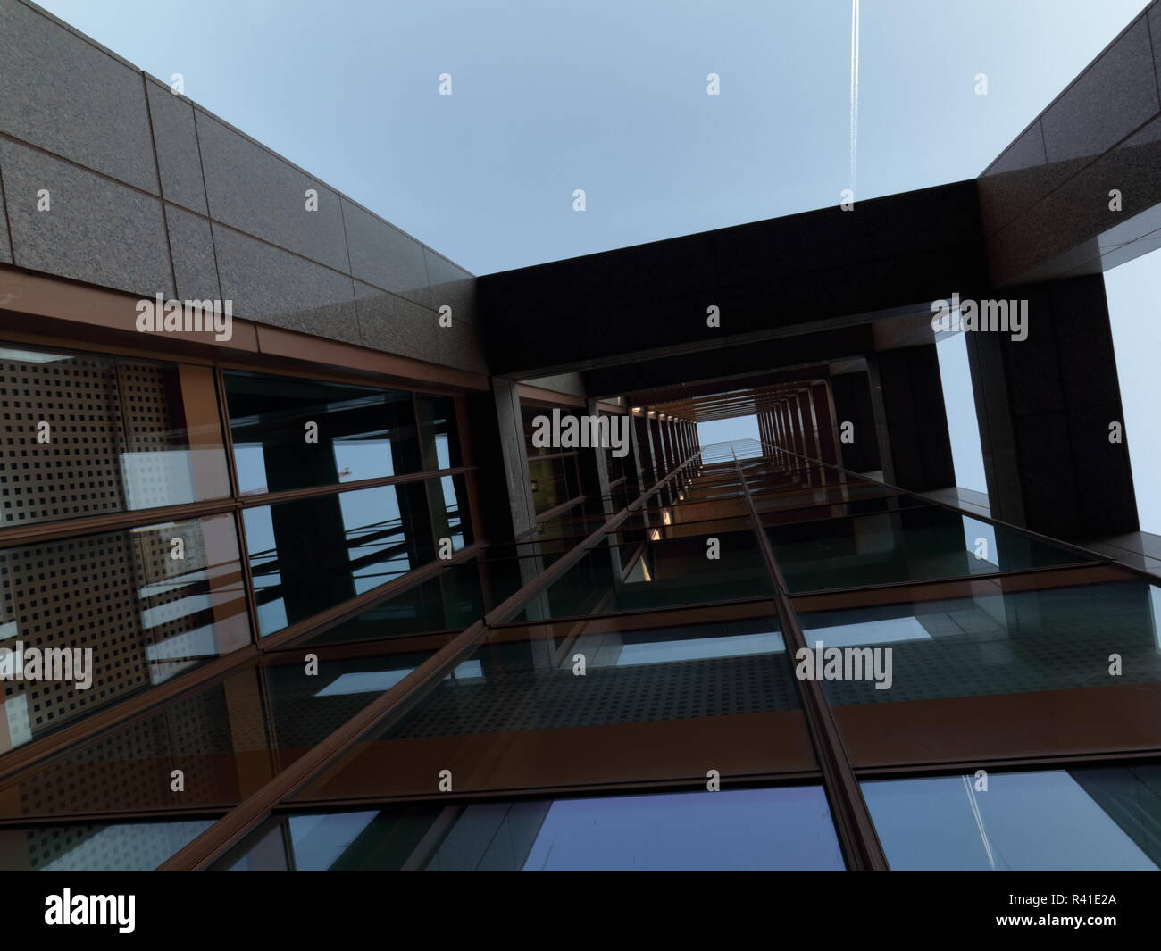 Look up at the tall building structure. Blue sky with plane flying past ...