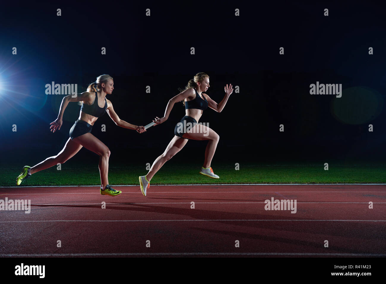 athletic runners passing baton in relay race Stock Photo - Alamy