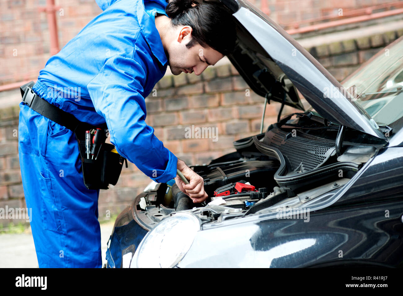 Young male mechanic fixing car engine Stock Photo - Alamy