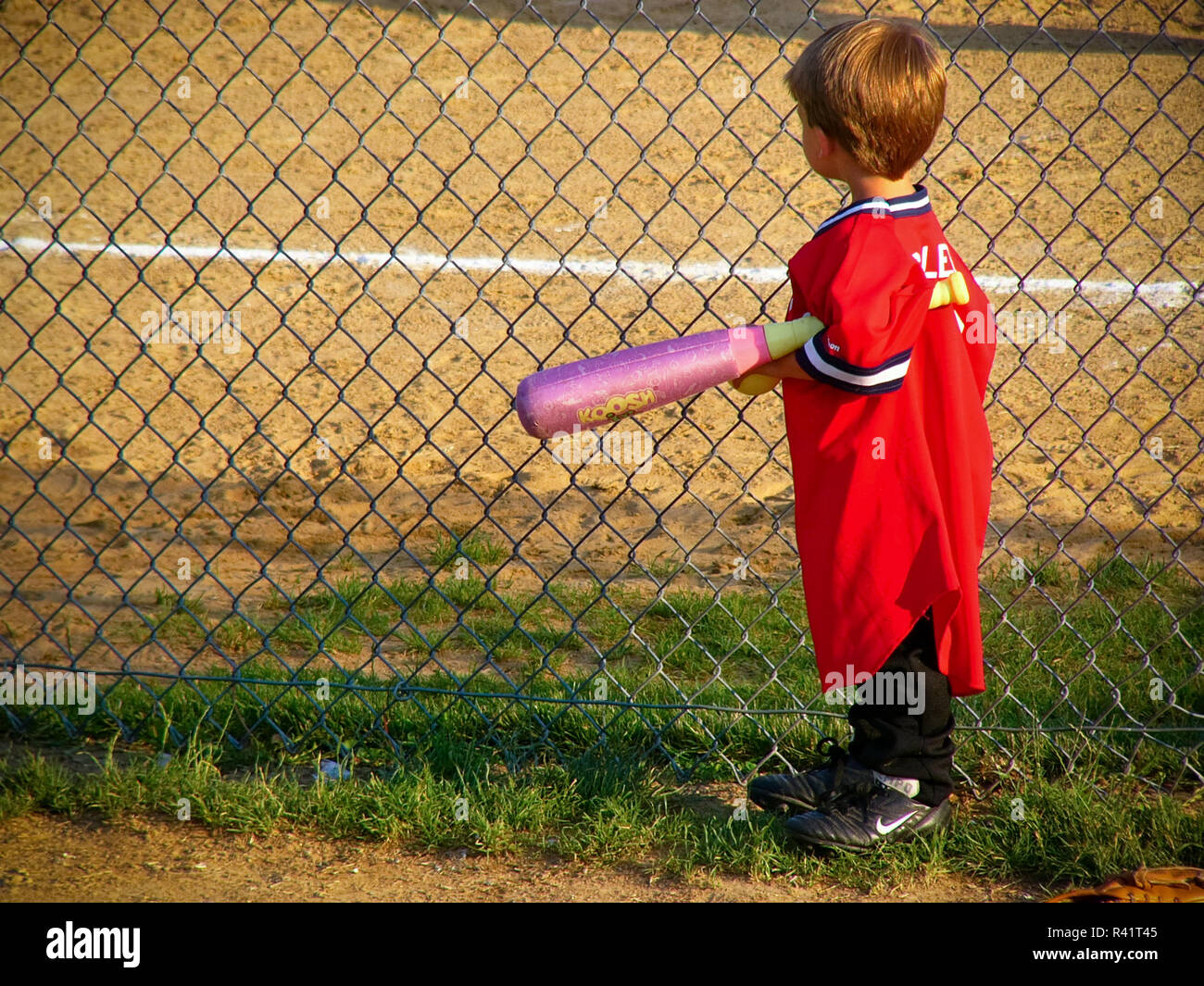A little brother of a baseball player looks longingly at the field ...