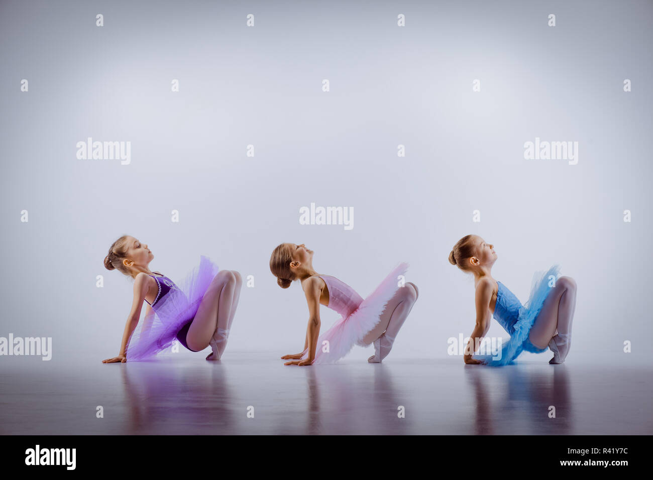 Three little ballet girls sitting in tutus and posing together Stock ...