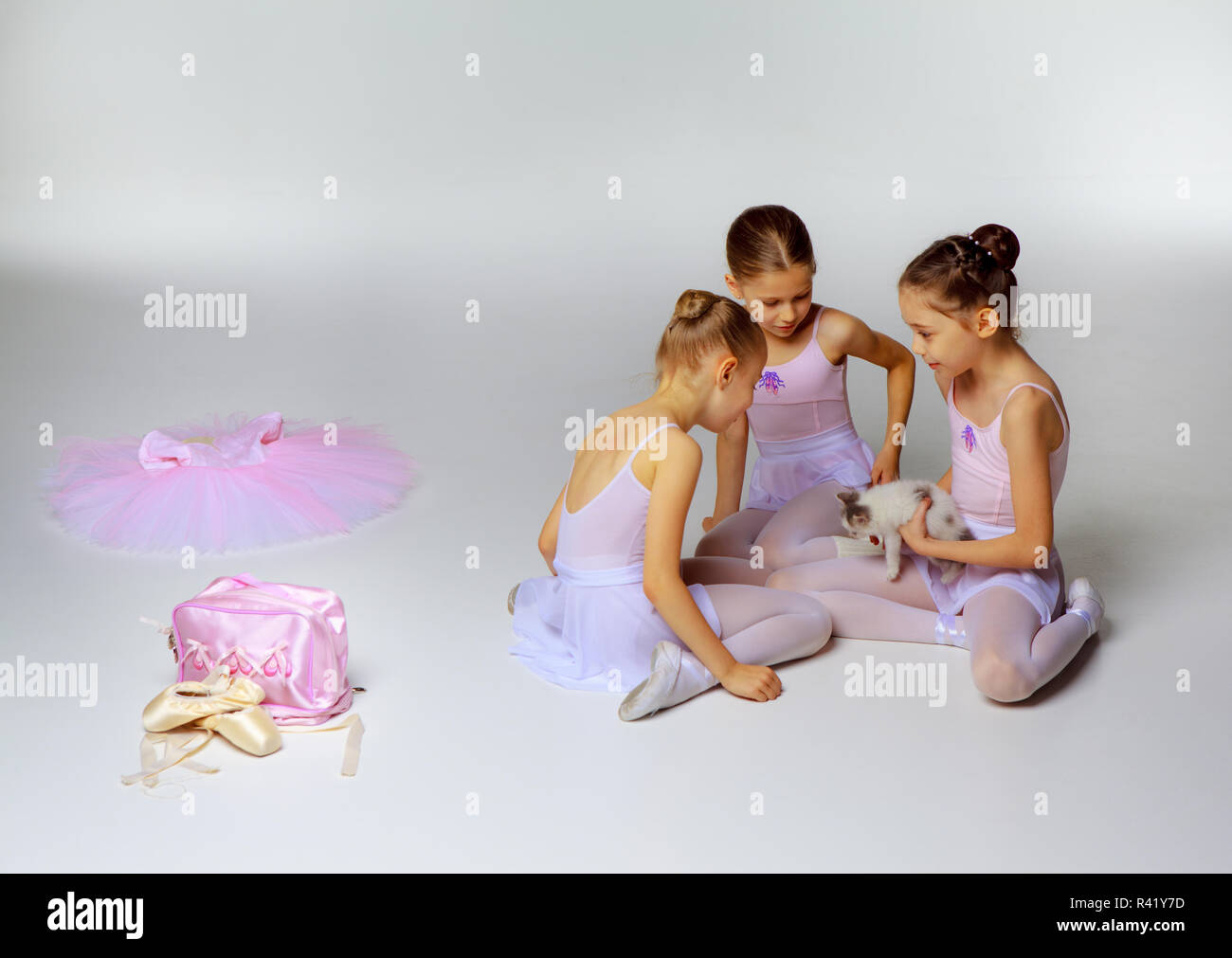 Three little ballet girls sitting in tutus and posing together Stock ...