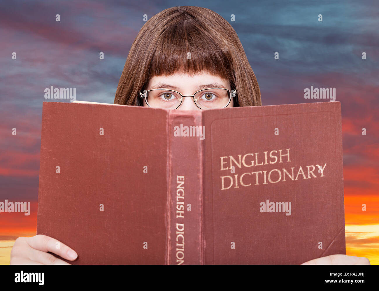 girl looks over English Dictionary and sunset sky Stock Photo - Alamy