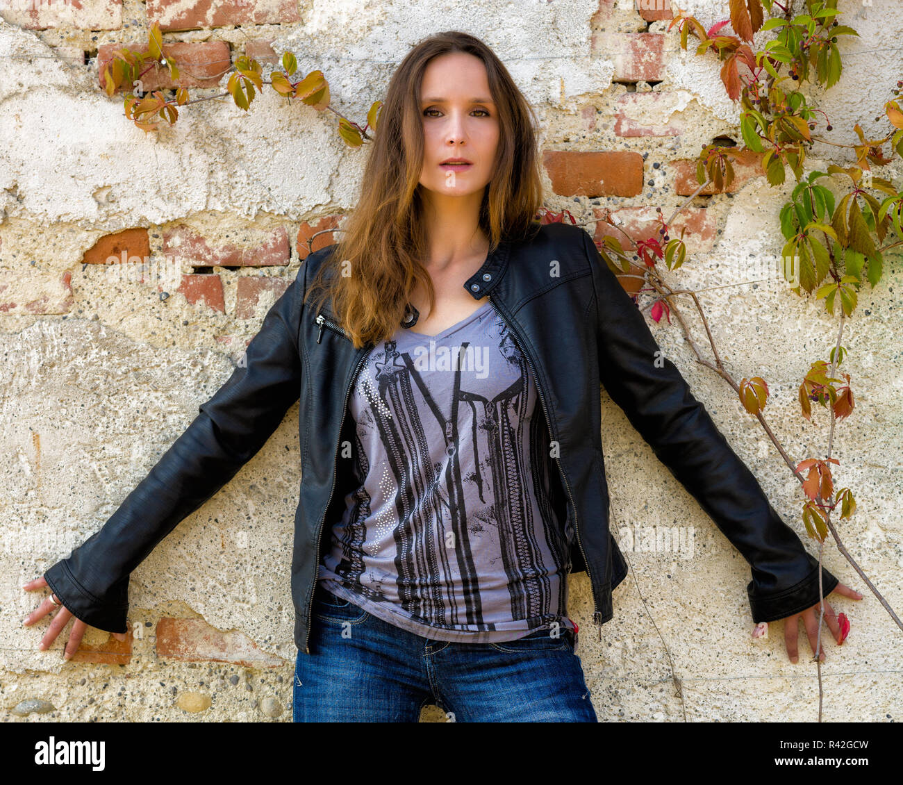Trendy woman posing in front of a weathered wall Stock Photo - Alamy
