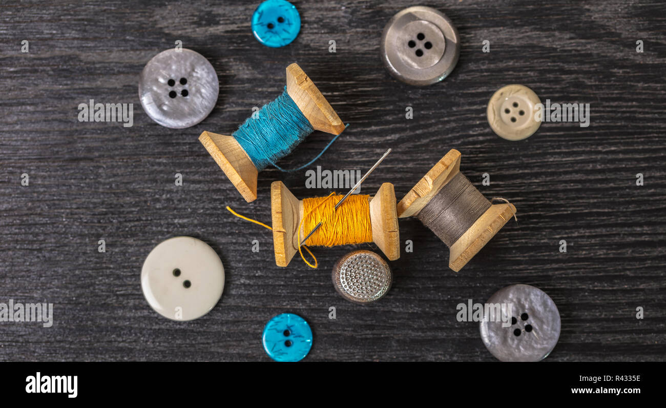 spool of threads and buttons on a wooden background Stock Photo - Alamy