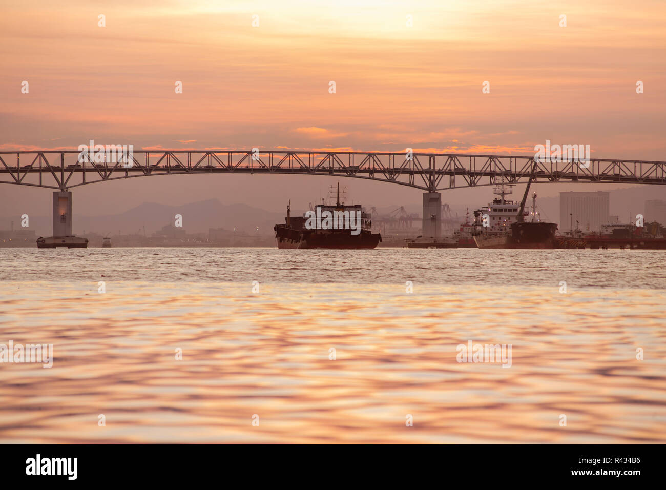 Traffic on bridge and sea crossing Mactan Bridge Cebu in misty dusk and ...