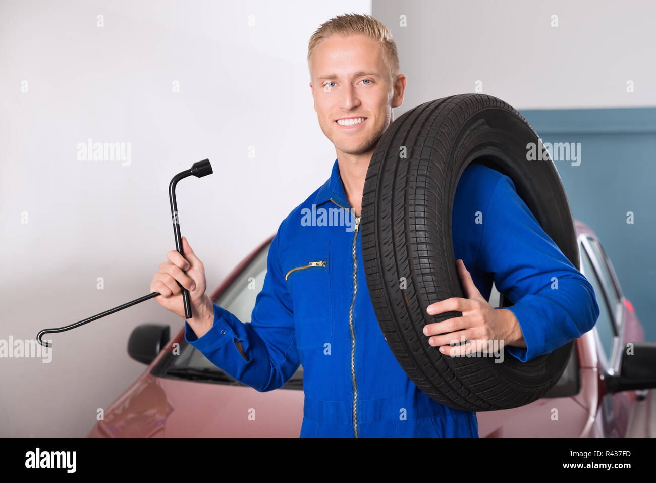 Smiling Mechanic Holding Tire And Wrench Stock Photo - Alamy