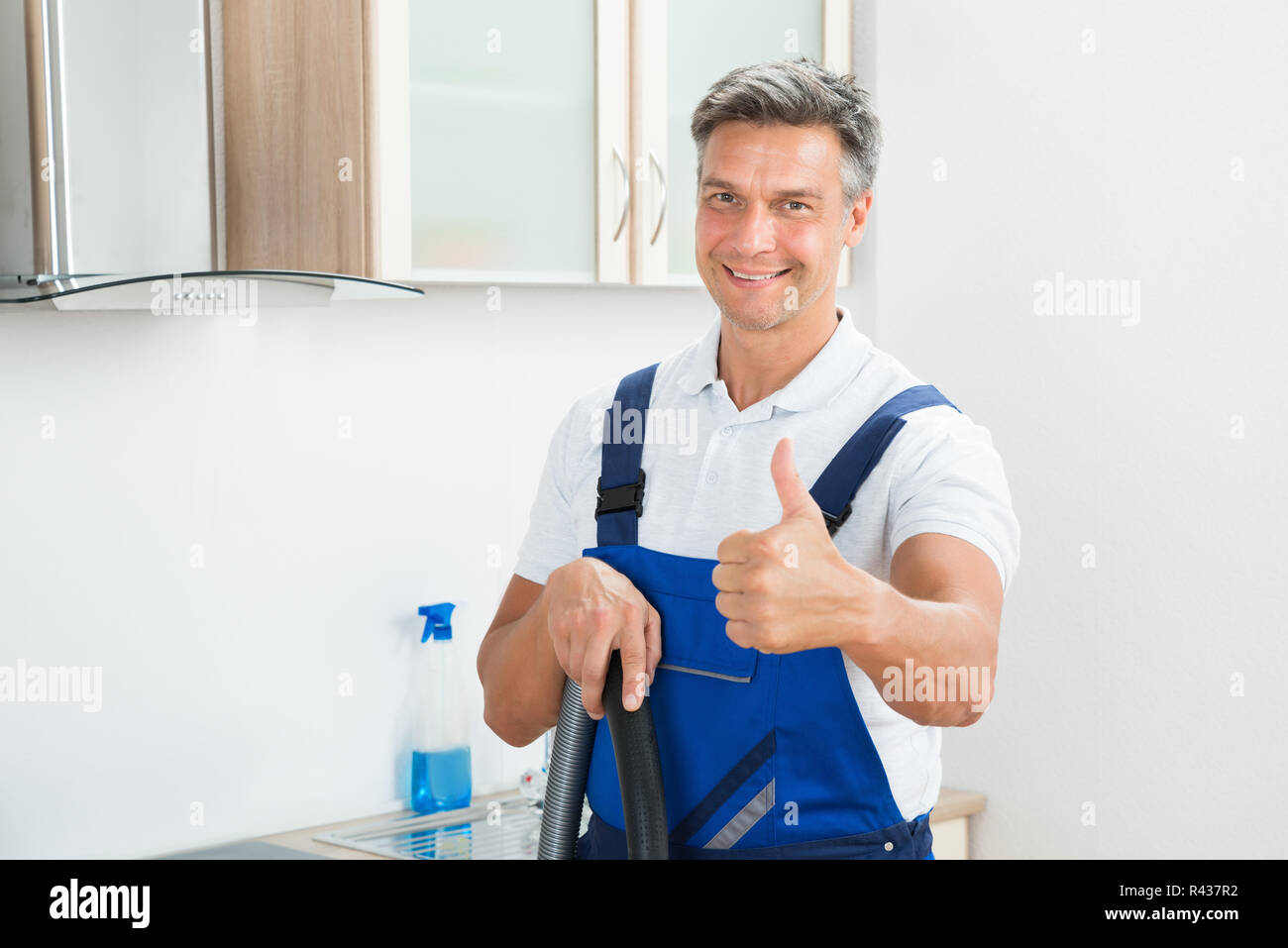 Happy Janitor Gesturing Thumbs Up In Kitchen Stock Photo - Alamy