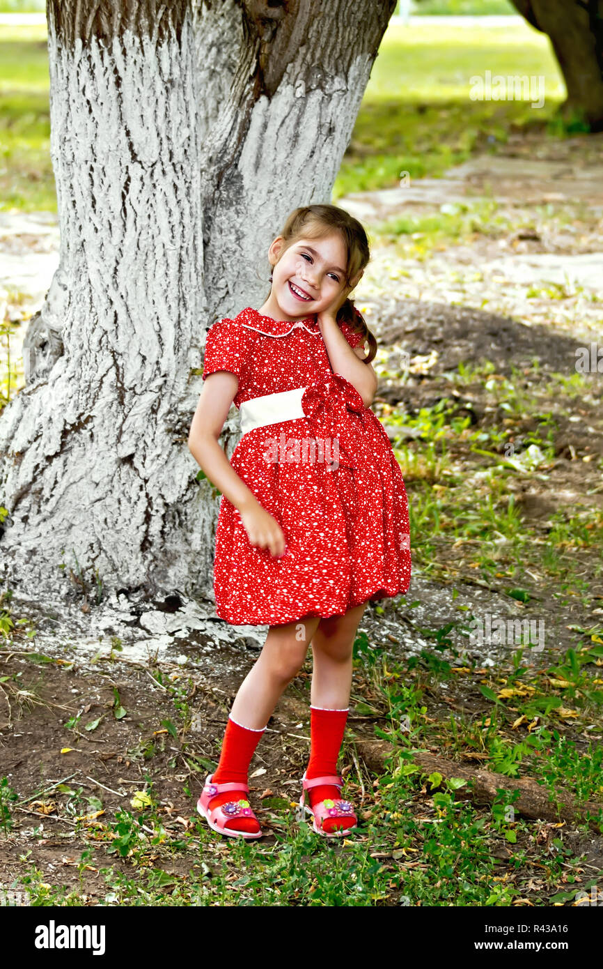Girl in red dress under tree in the park Stock Photo - Alamy