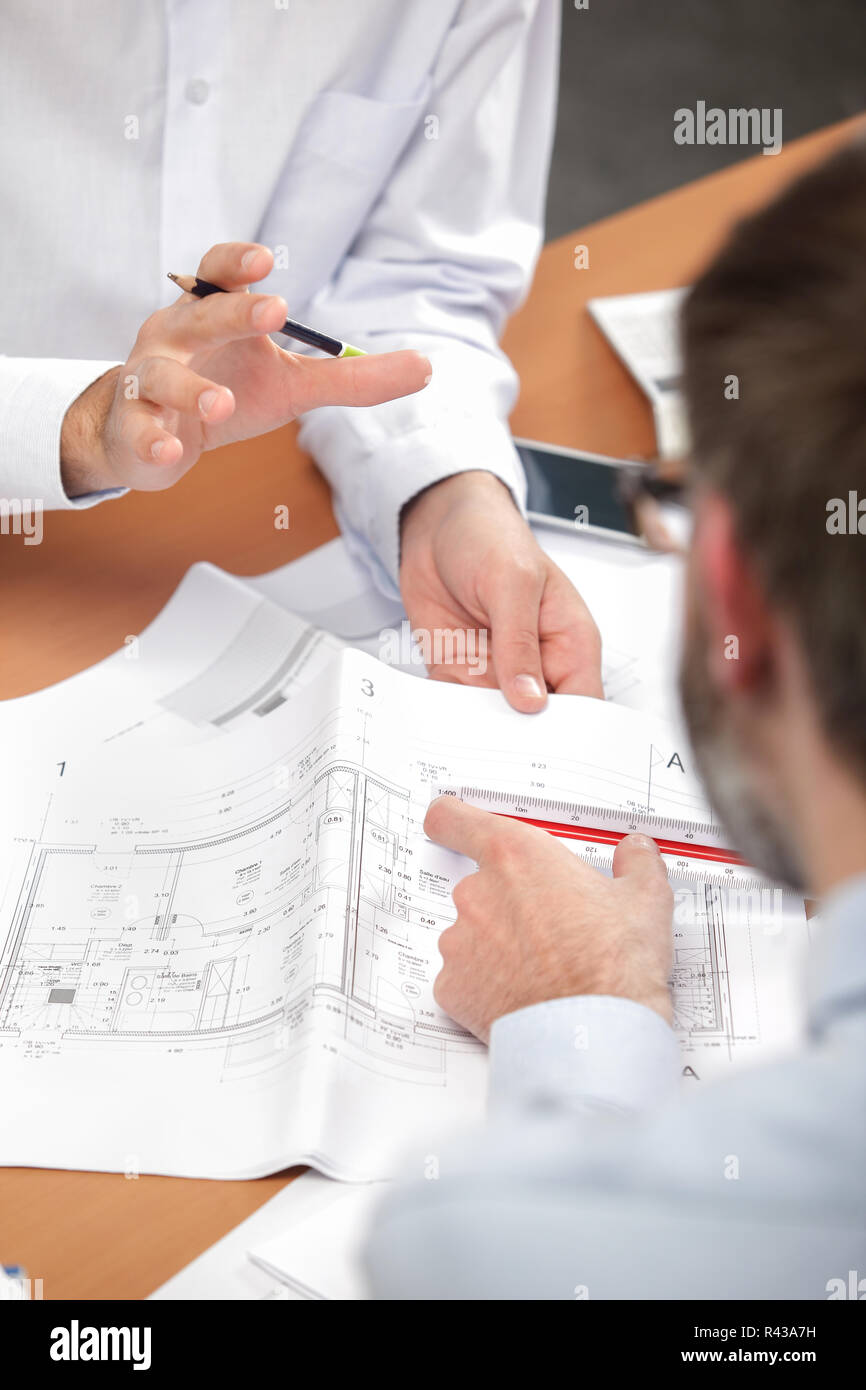 Architects gathered around plans Stock Photo - Alamy
