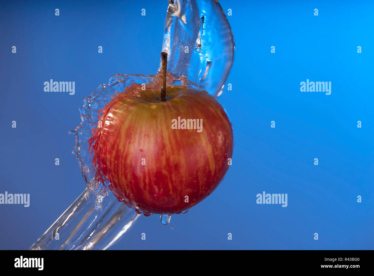 Organic red apple water splash blue background Stock Photo - Alamy