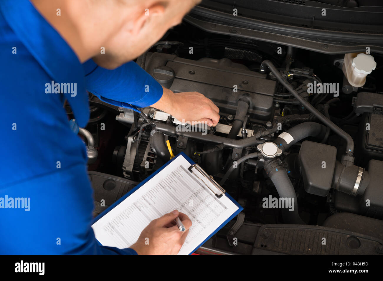 Mechanic Standing Near Car Writing On Clipboard Stock Photo - Alamy