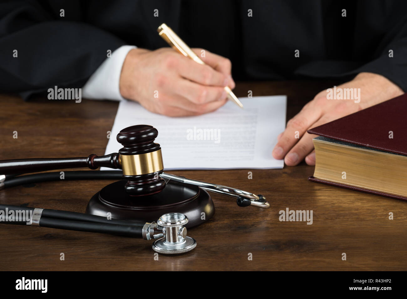 Judge Writing On Document With Mallet And Stethoscope At Desk Stock ...