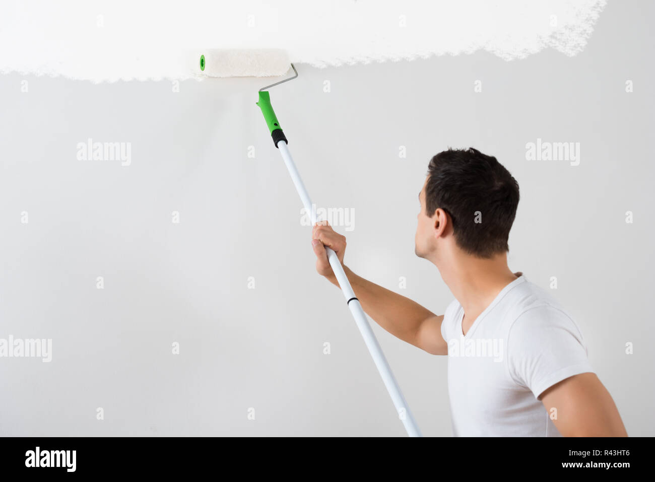 Man Painting Wall With Paint Roller Stock Photo - Alamy