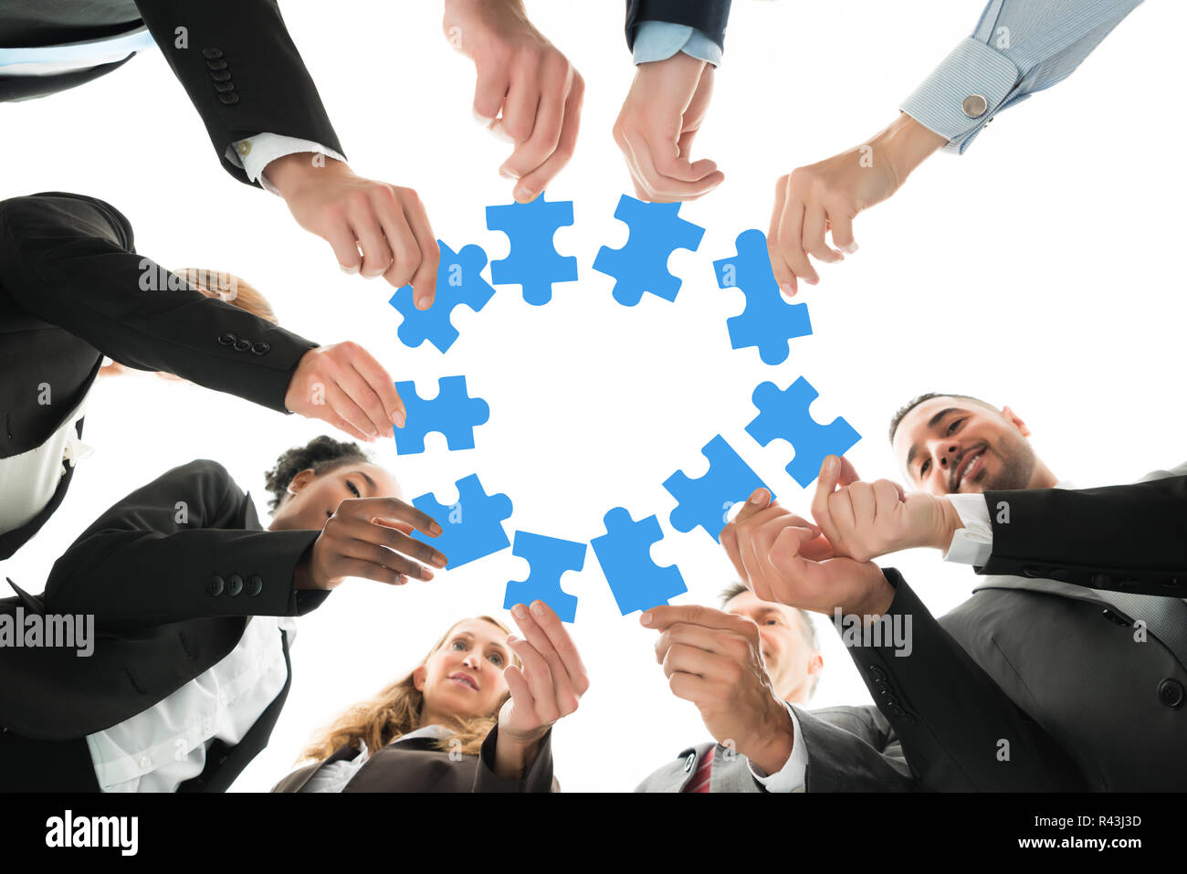 Business Team Joining Jigsaw Pieces In Huddle Stock Photo - Alamy