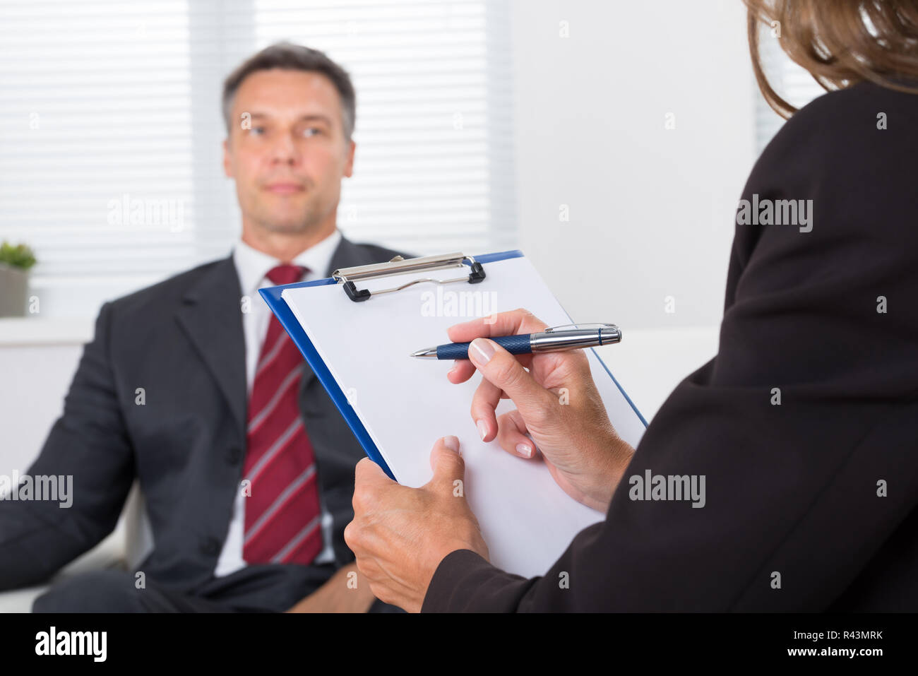 Psychiatrist Writing On Clipboard In Front Of Patient Stock Photo - Alamy