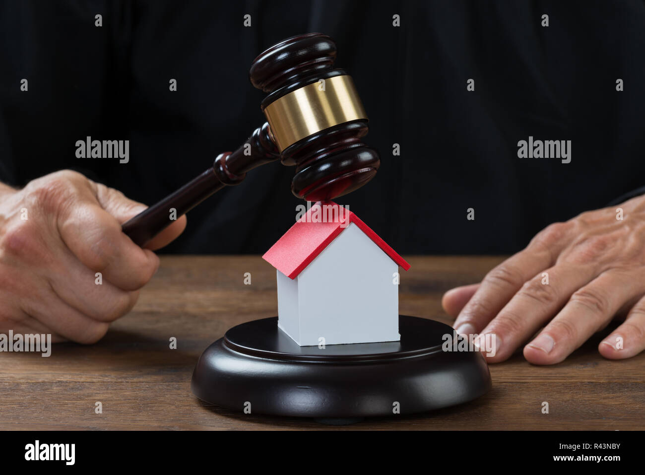 Judge Holding Gavel On House At Desk Stock Photo - Alamy