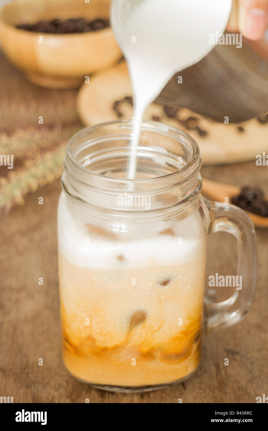 Milk pouring for fresh iced coffee Stock Photo - Alamy