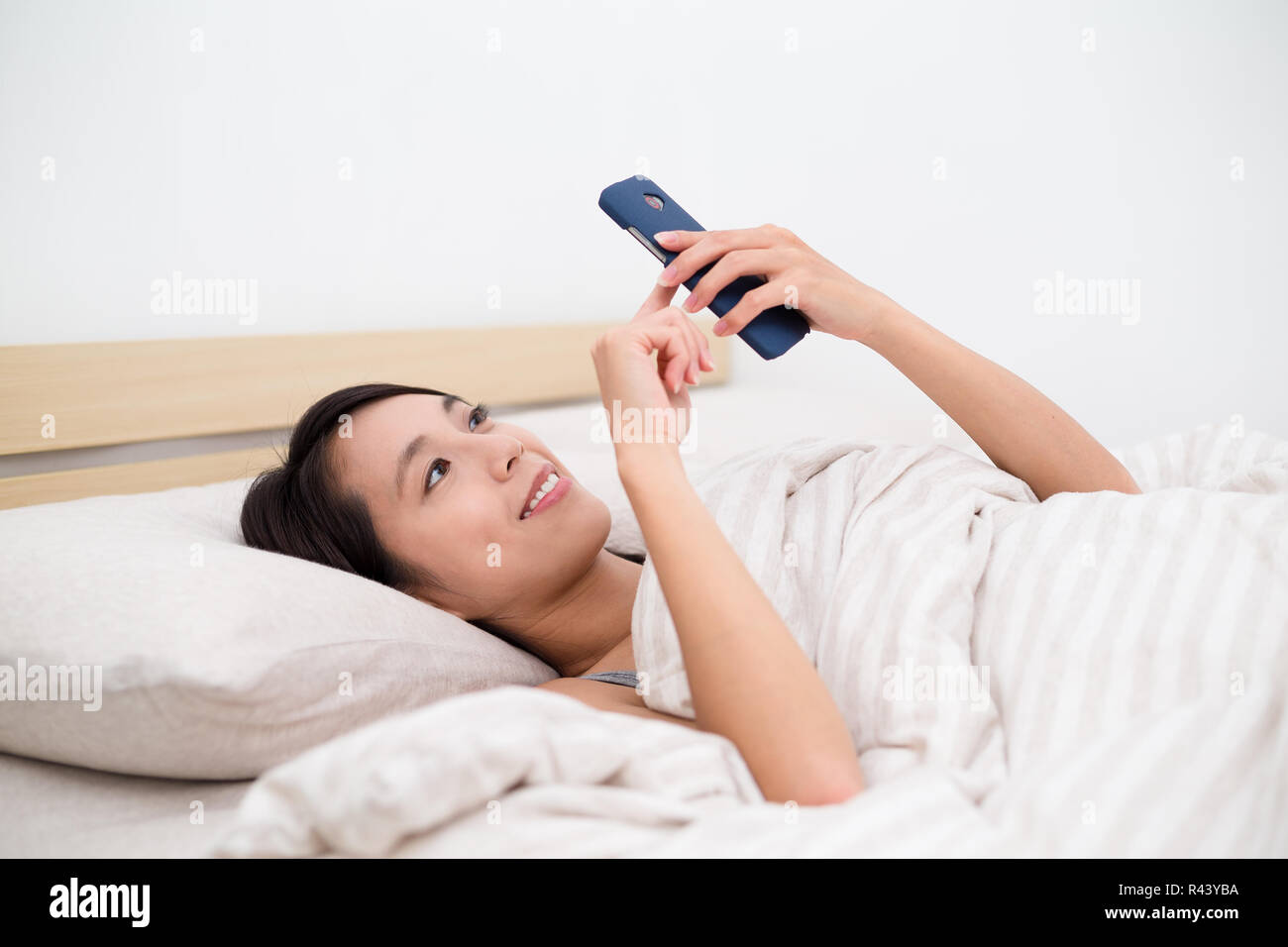 Asian Woman lying down on bed and using the mobile phone Stock Photo ...