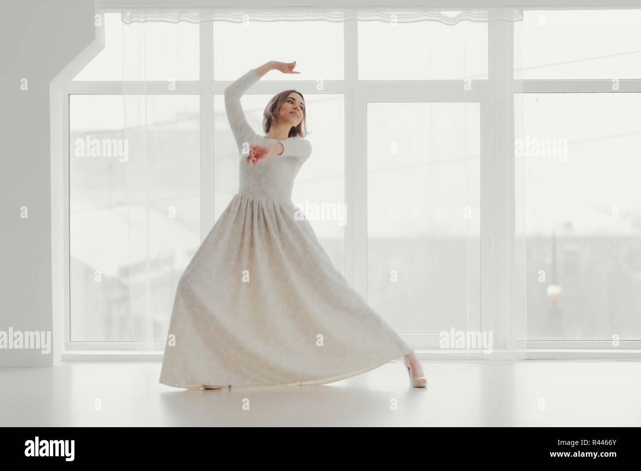 The girl in white is dancing on the background of large windows Stock ...