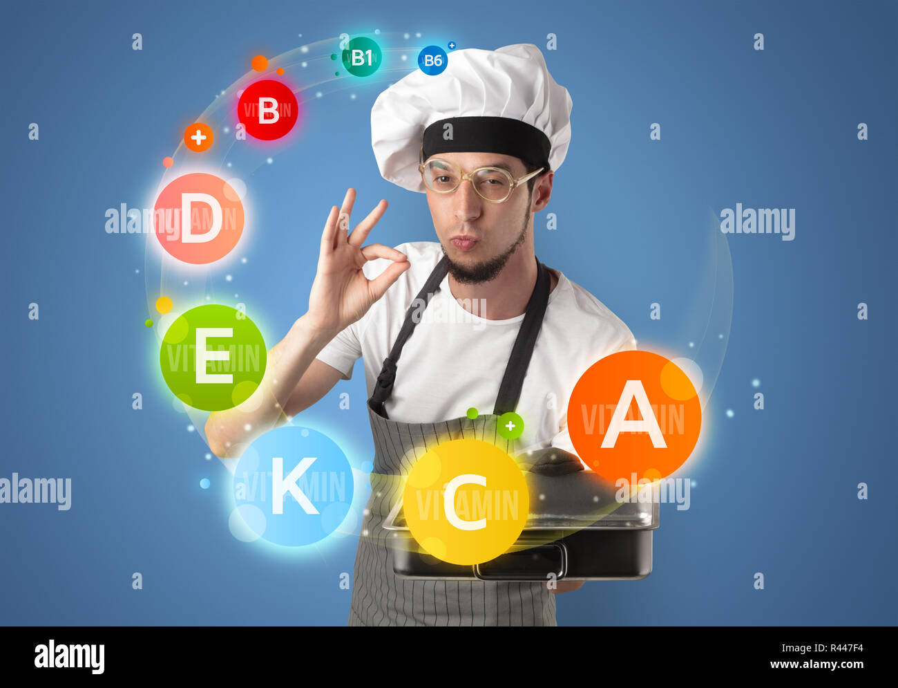 Handsome cook with kitchen instruments and vitamin concept Stock Photo ...