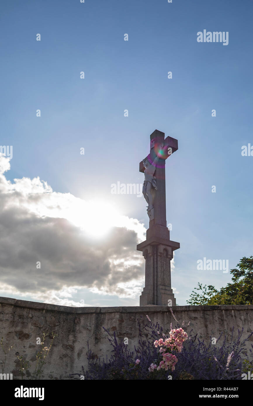 Statue of Jesus on a cross with bright sun light and rays coming ...