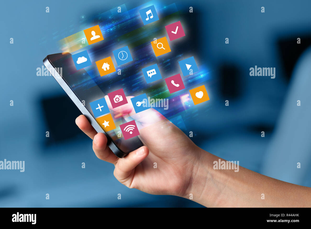Hand using phone with colorful fast moving application icons and ...
