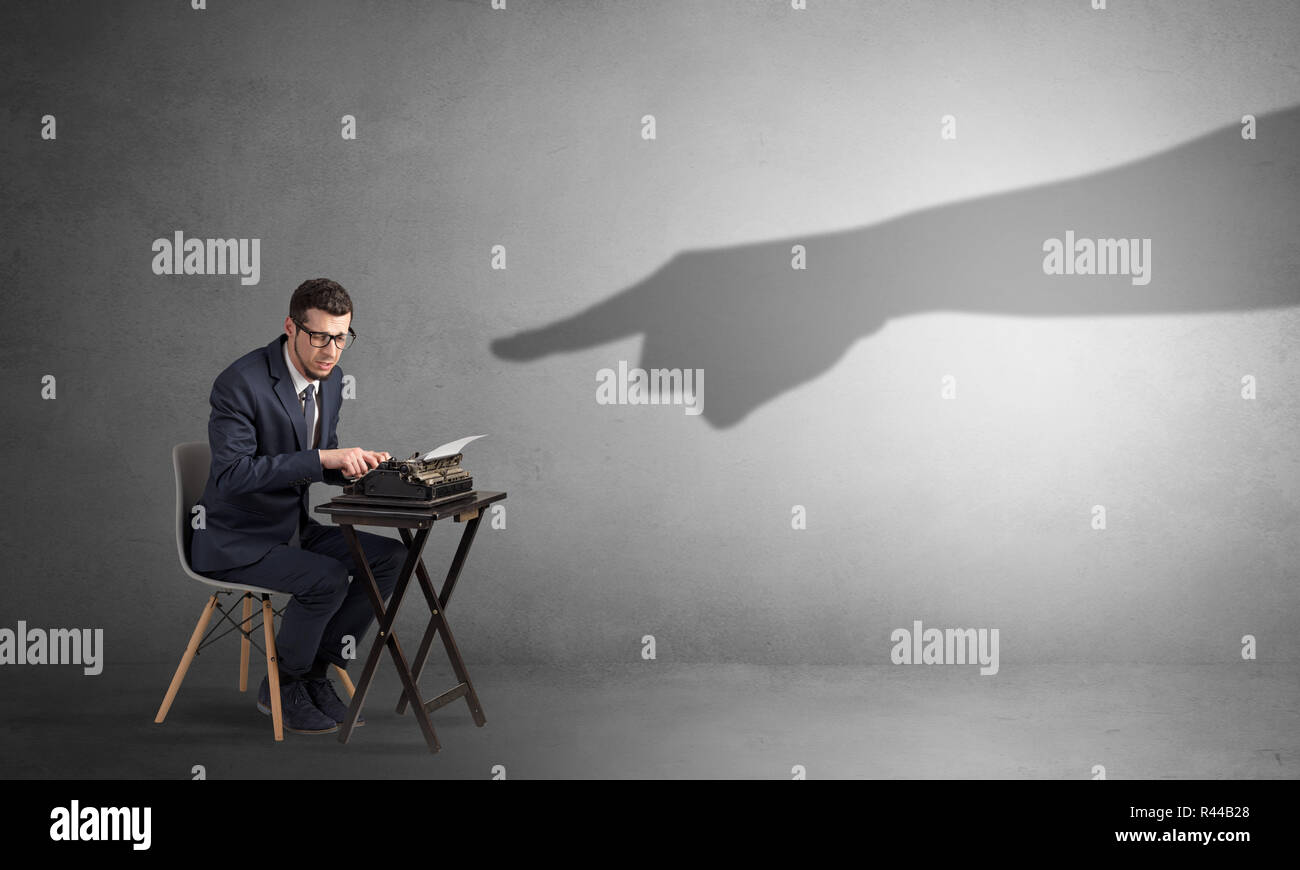 Shadow hand pointing at a small afraid worker Stock Photo - Alamy