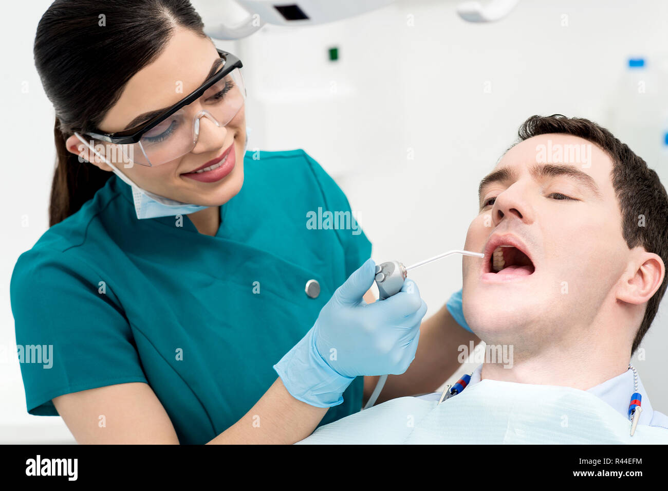 Pretty dentist cleaning gums of patient Stock Photo - Alamy