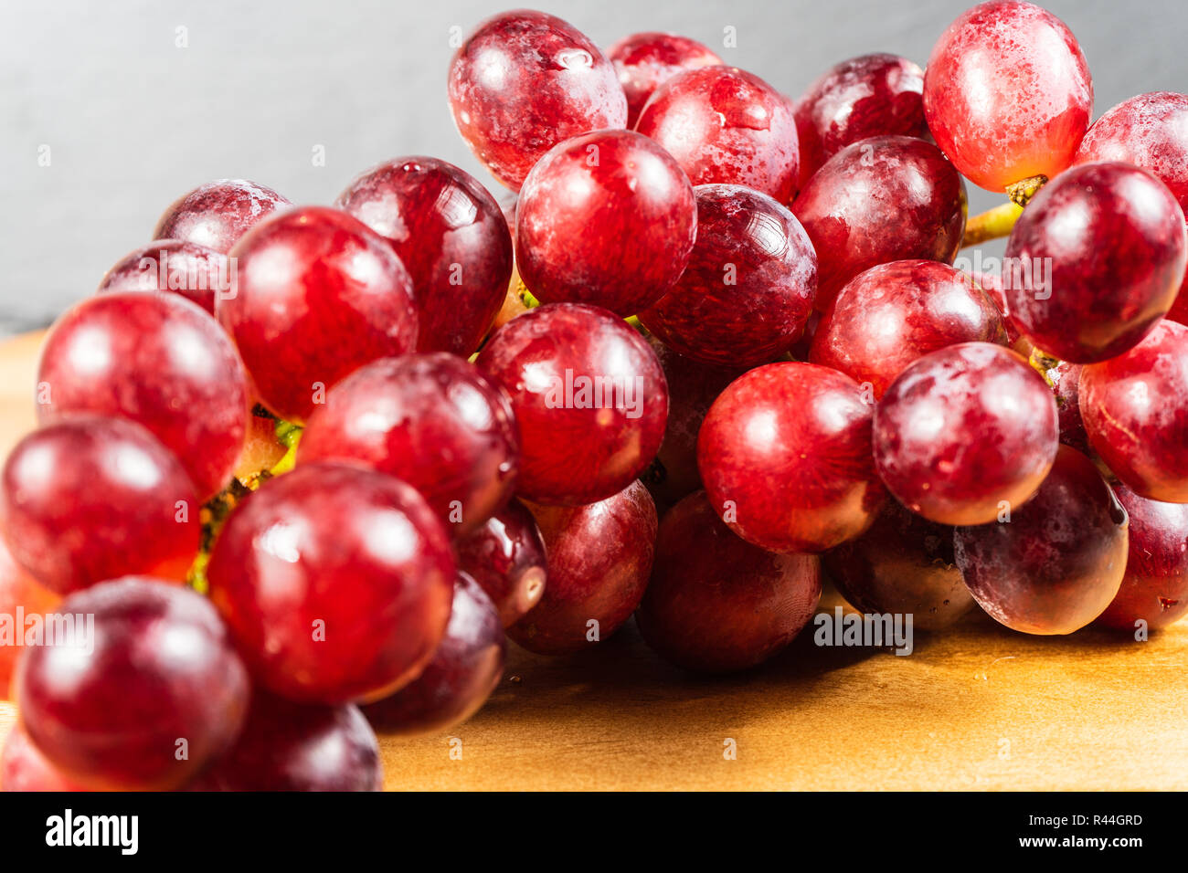 Grapes on wooden table, close-up.Bunches of fresh ripe red grapes on a ...
