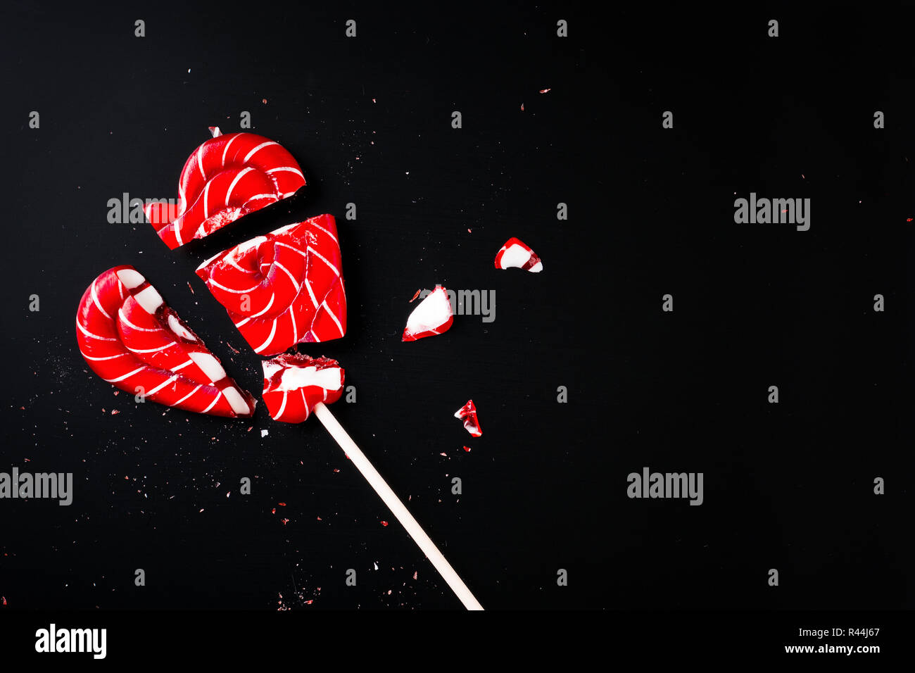 Broken lollipop in shape of heart on dark background with copy space ...