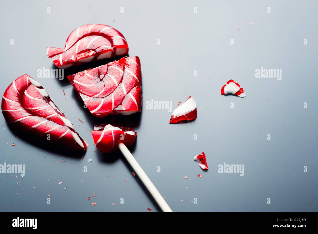 Broken lollipop in shape of heart on dark background with copy space ...