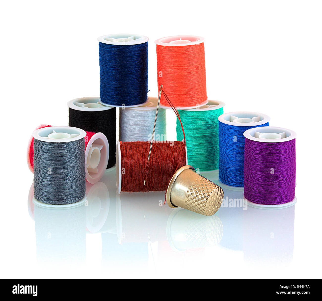 Colorful threads, thimble and needle isolated on white background with ...