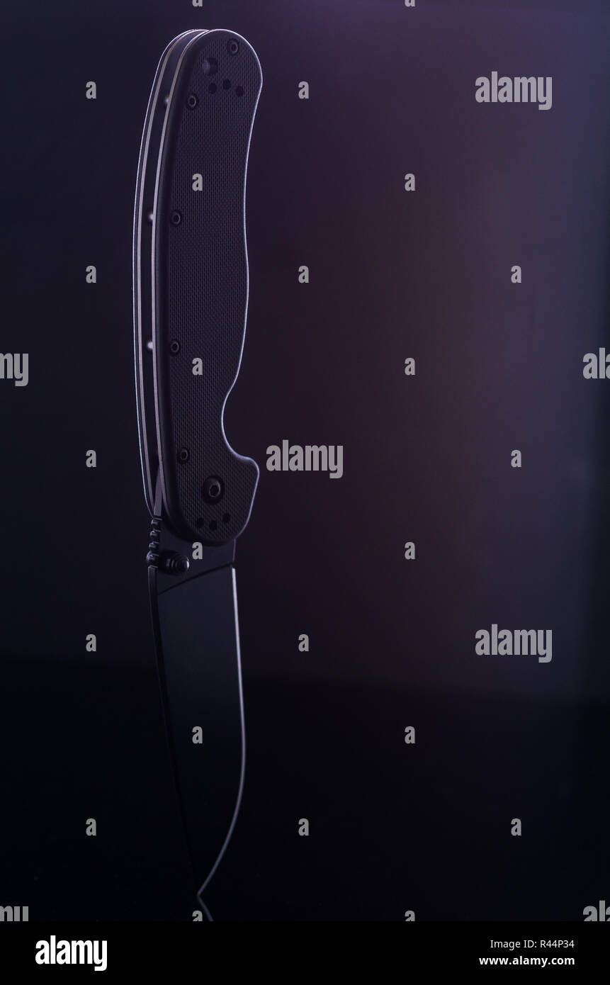 Big black knife on a black background. Folding black knife. Vertical ...