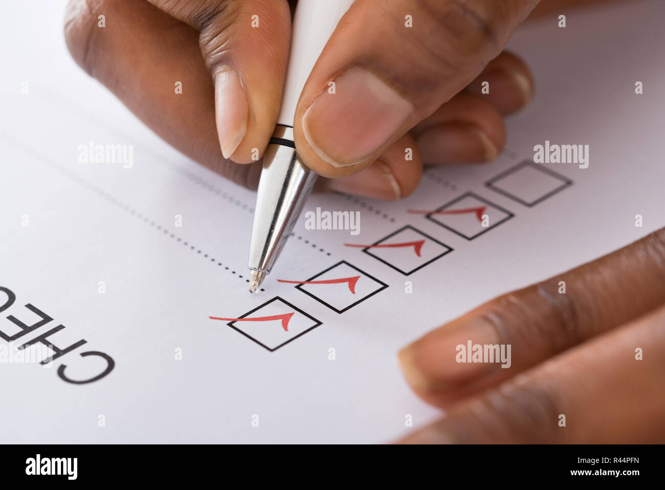 Person's Hand Marking On Checklist Form With Red Pen Stock Photo - Alamy