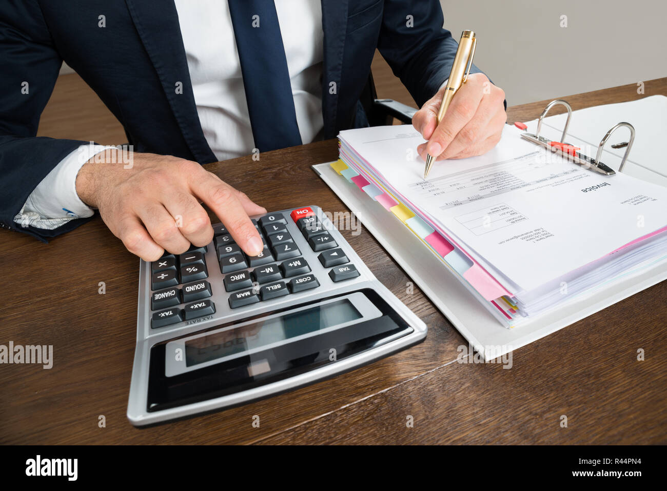 Businessman Using Calculator While Checking Invoice At Desk Stock Photo ...