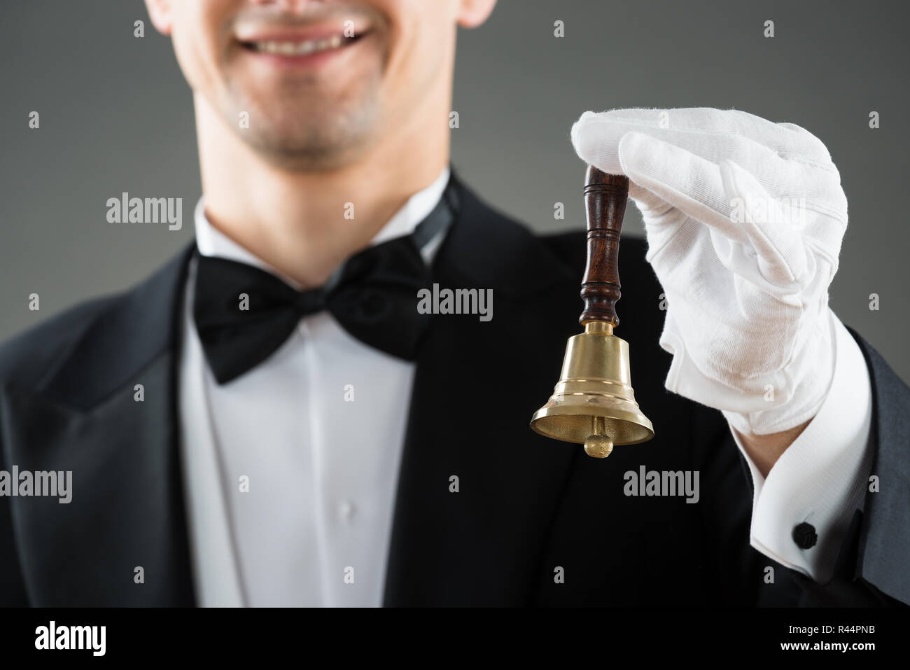 Midsection Of Waiter Holding Ring Bell Stock Photo - Alamy