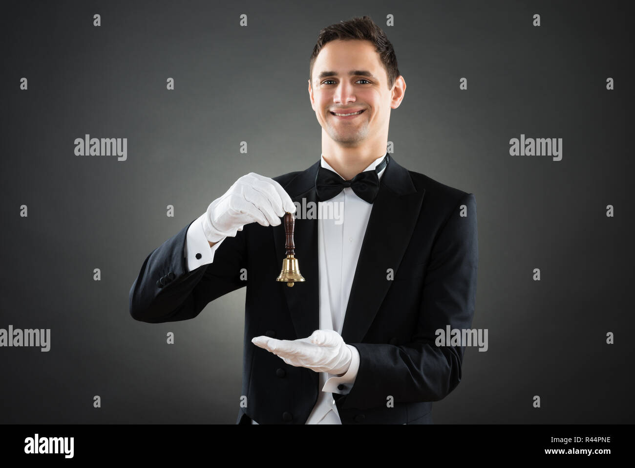 Portrait Of Happy Waiter Holding Ring Bell Stock Photo - Alamy