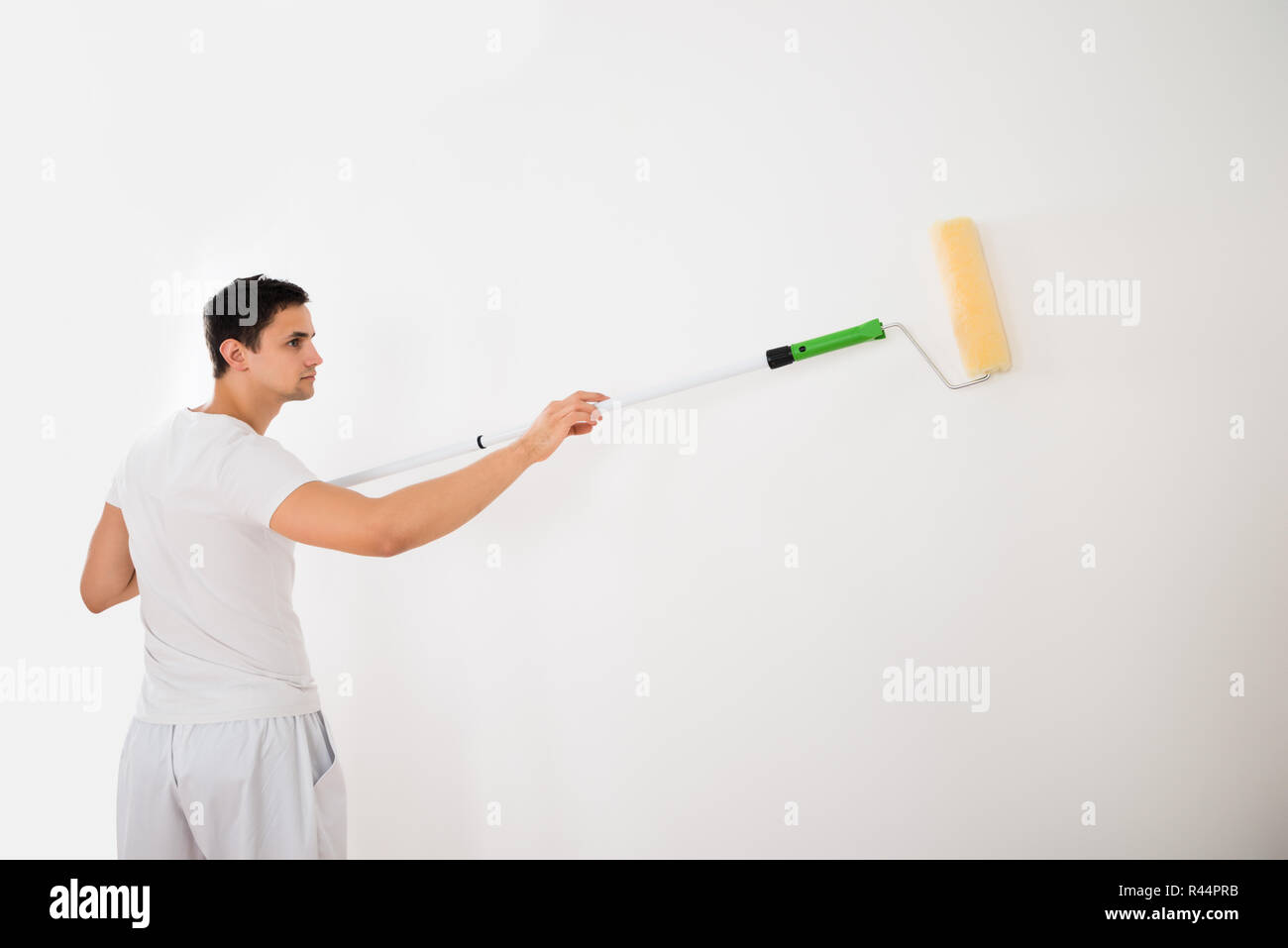 Man Using Paint Roller On White Wall Stock Photo - Alamy