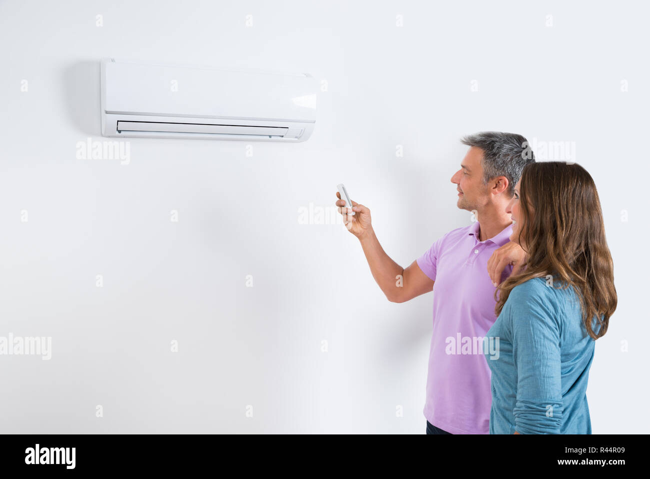 Couple Adjusting Temperature Of Air Conditioner Stock Photo - Alamy