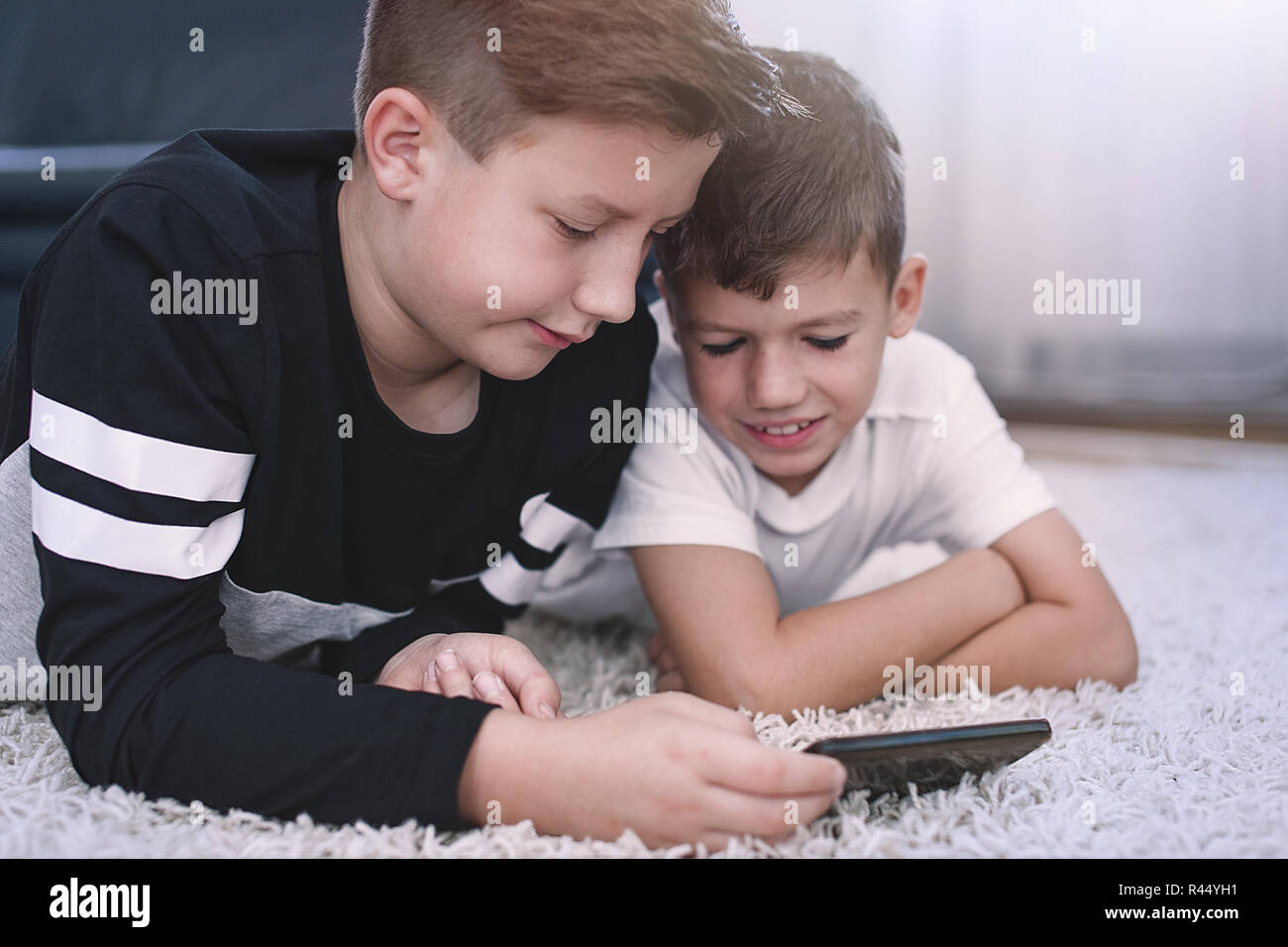 Little boys using smartphone on carpet at home Stock Photo - Alamy