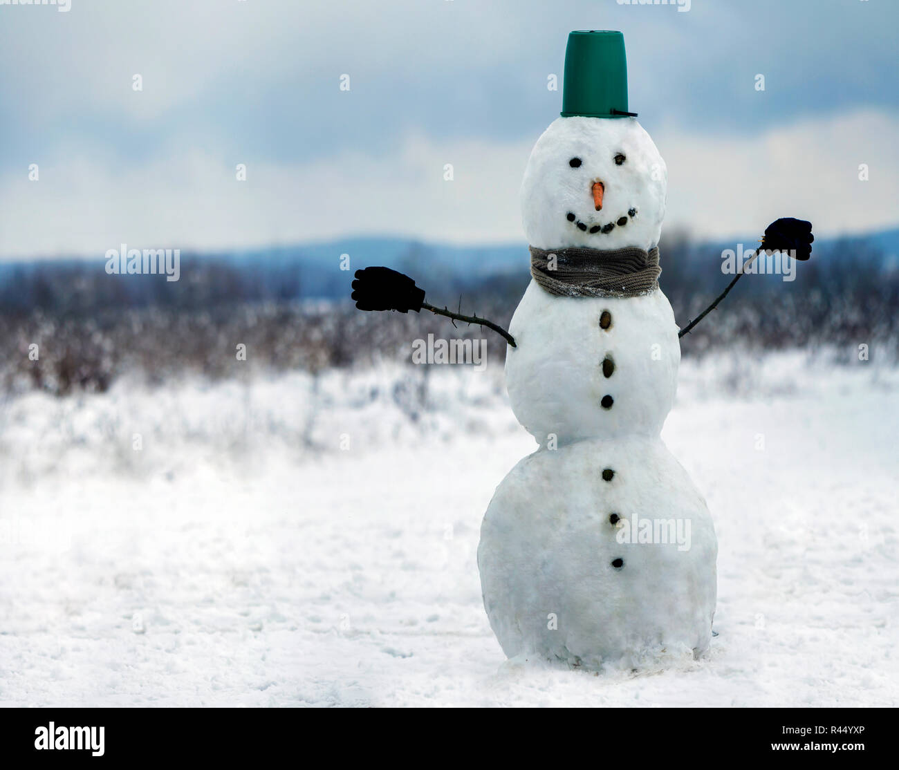 Big smiling snowman with bucket hat, scarf and gloves on white snowy ...