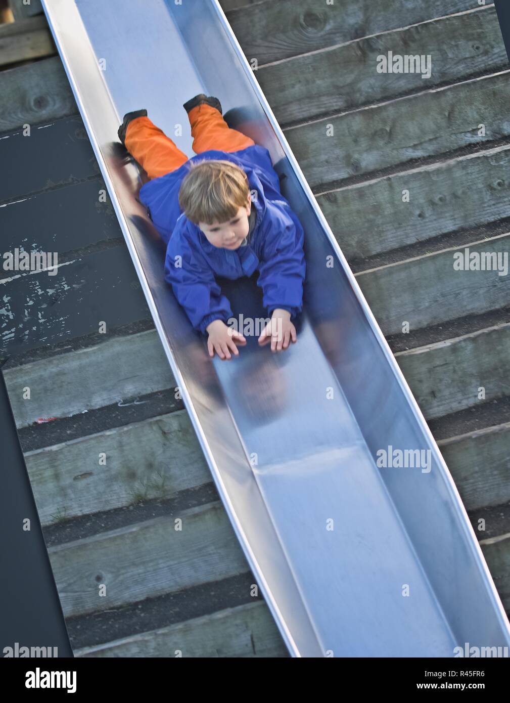 young boy slides down a sliding board head first Stock Photo - Alamy