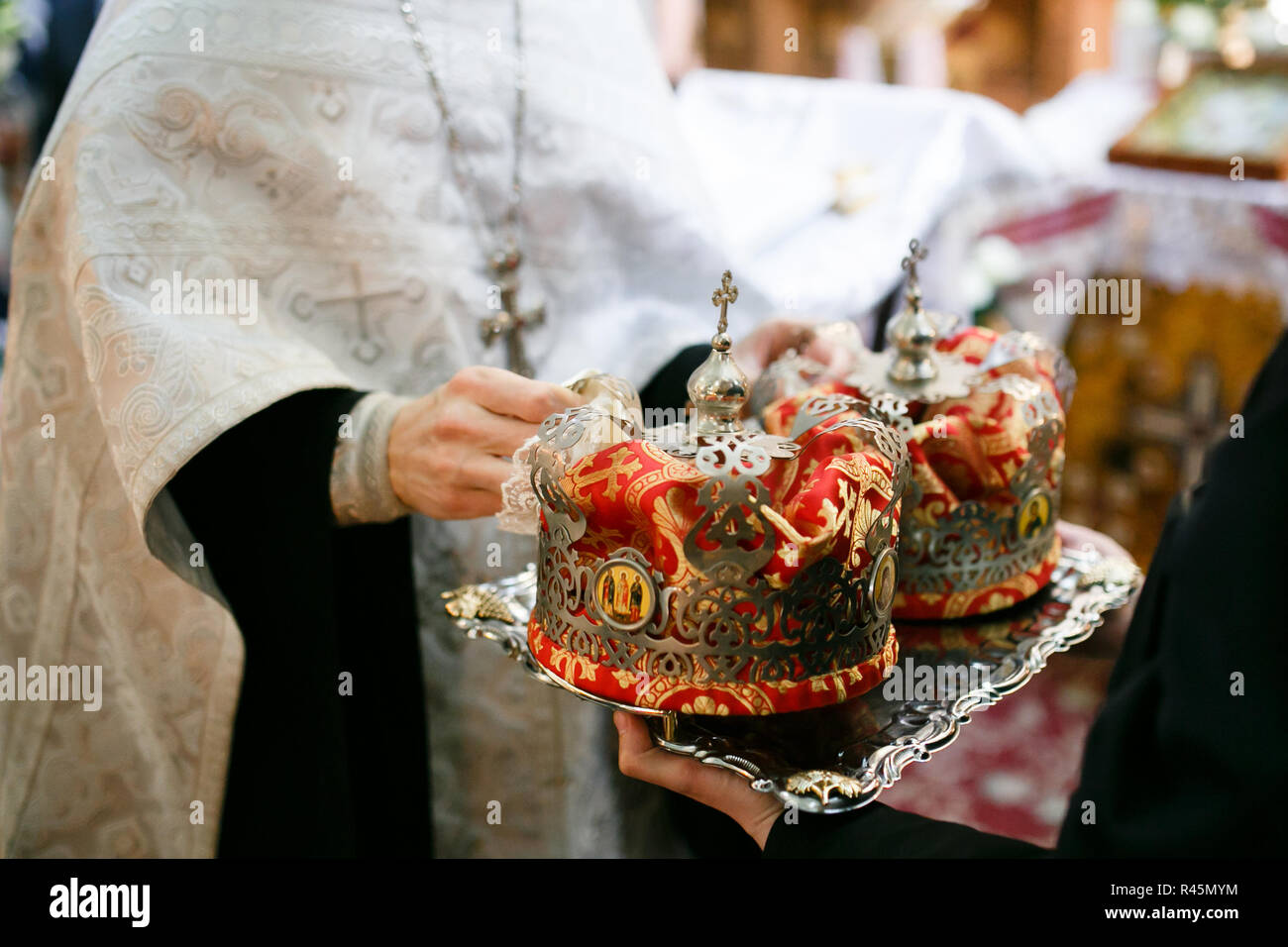 Priest picks up ritual crowns for weddings in church Stock Photo - Alamy