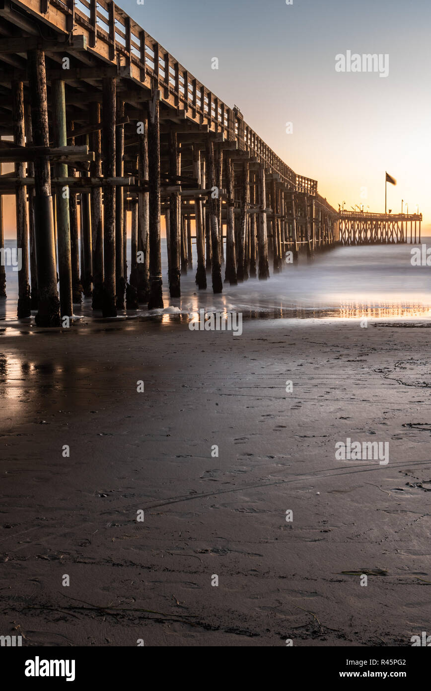 Last Light fading behind the ocean horizon as reflecting wet sand and ...