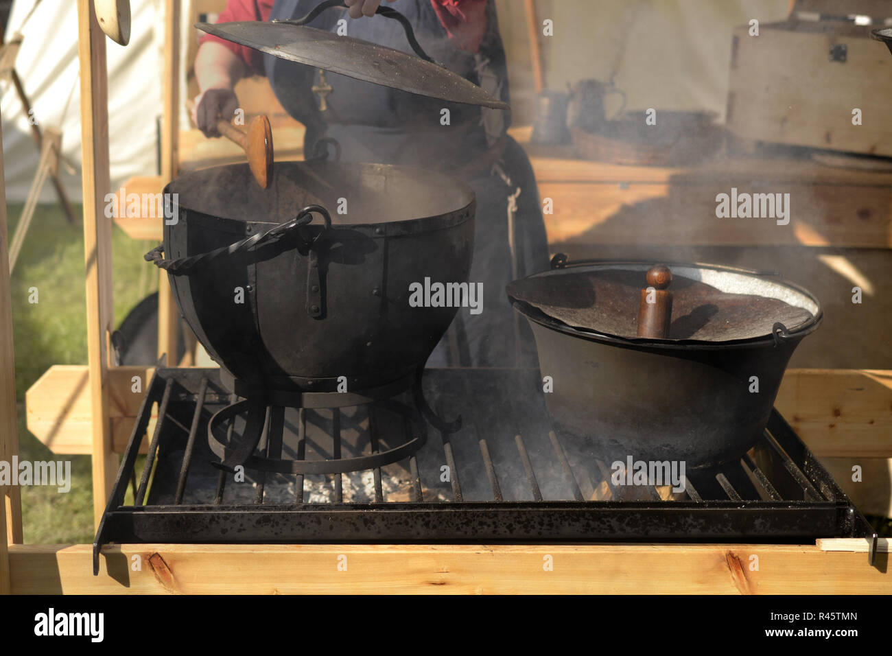 medieval pots on a hearth and a woman with a cooking spoon Stock Photo ...