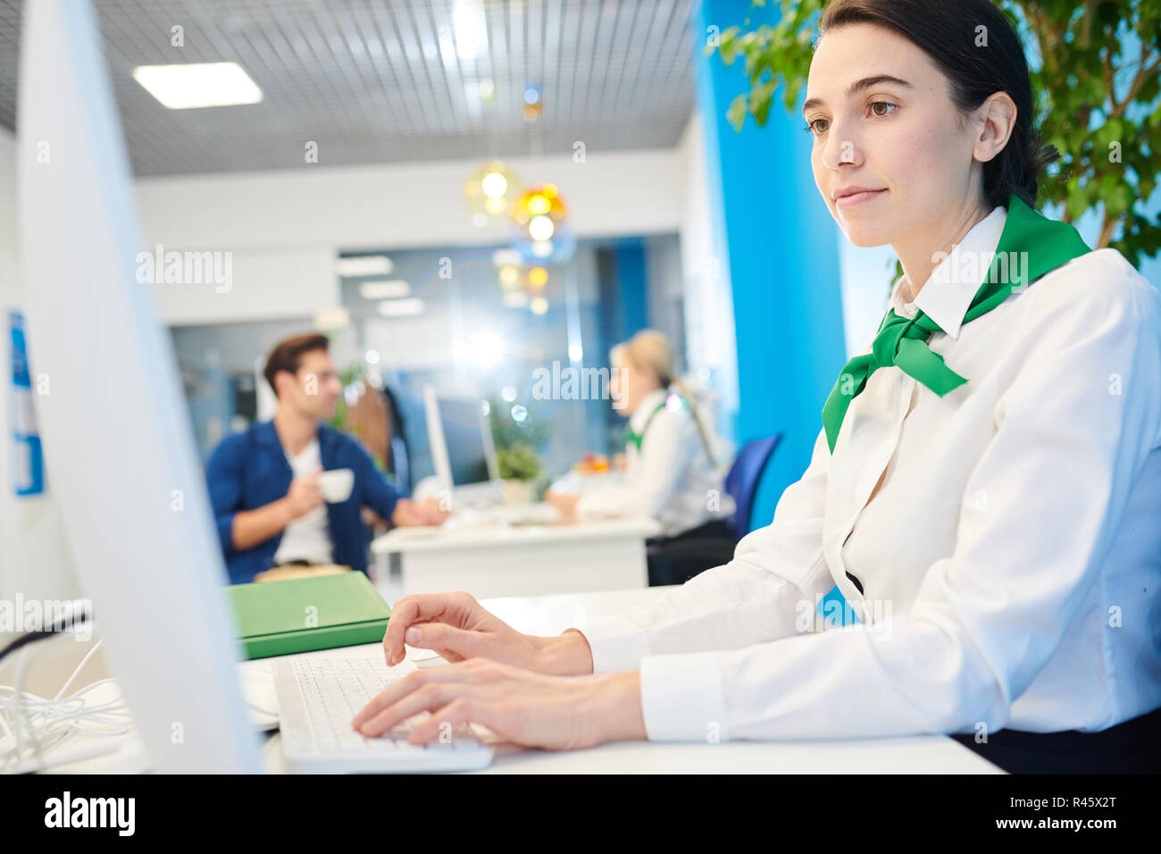 Busy bank representative adding information into computer Stock Photo ...